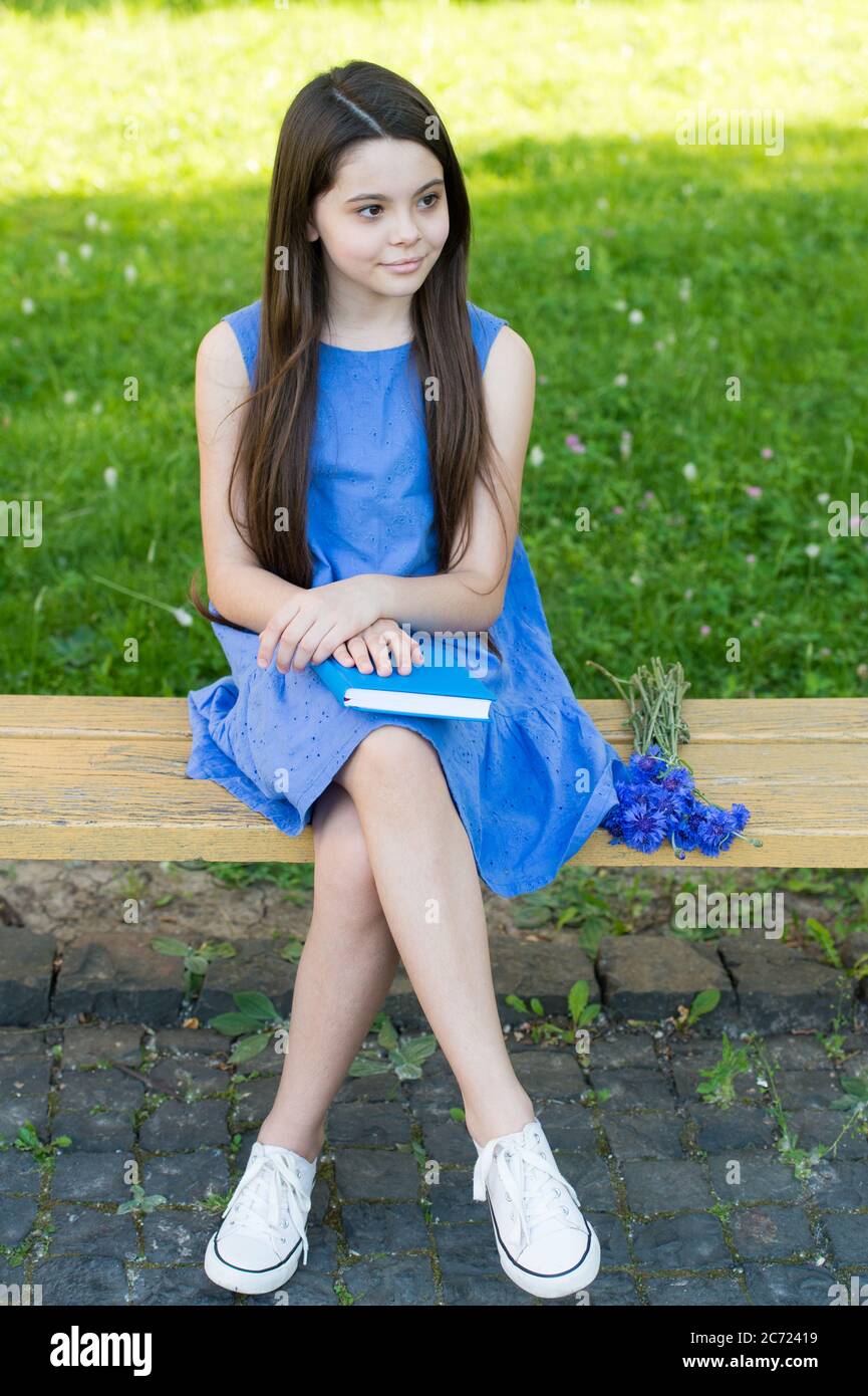 Summer fun has begun. Little child sit on park bench. Small girl relax ...