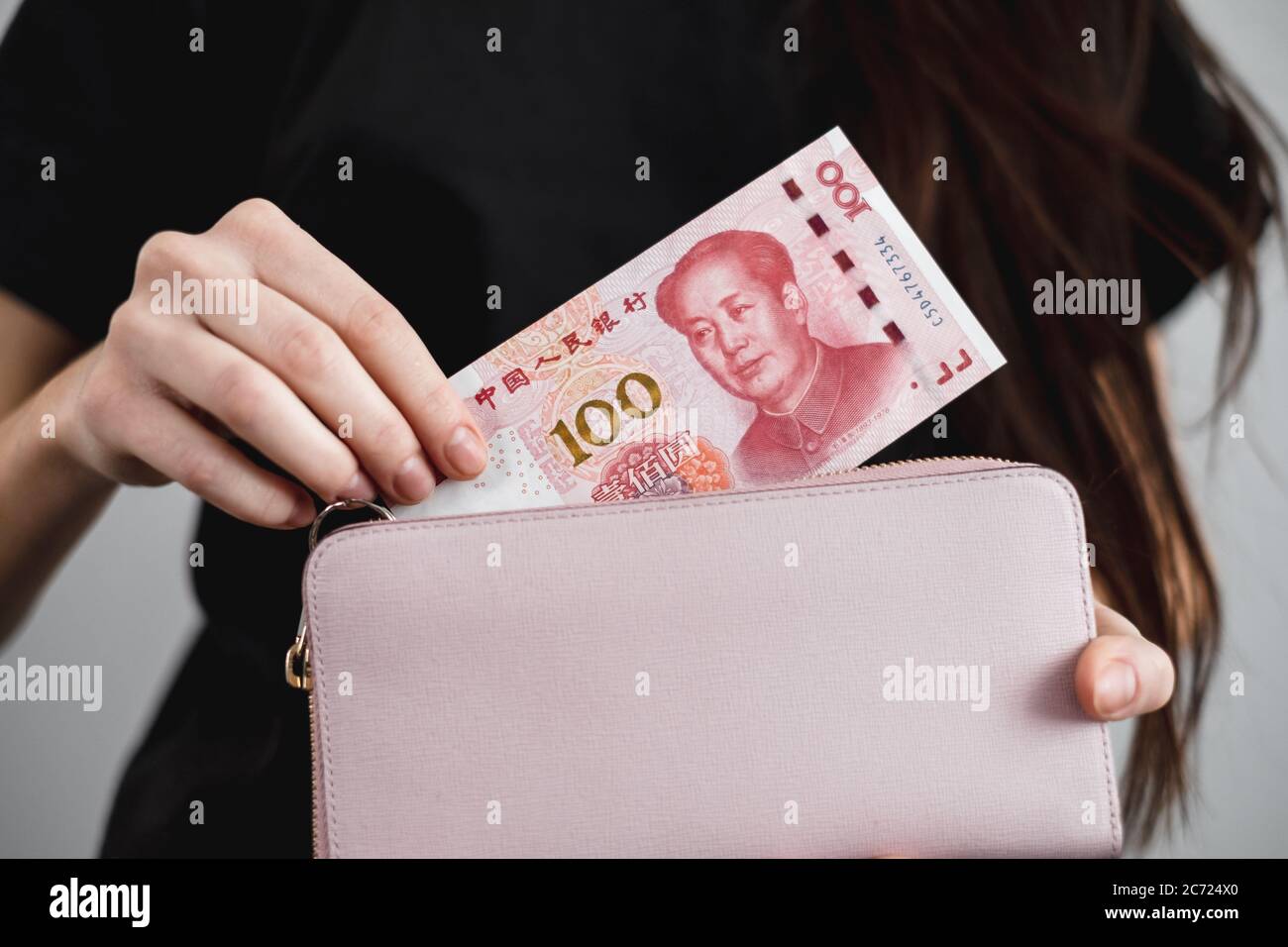 Young woman takes out money chinese yuan banknotes from a wallet. Close ...