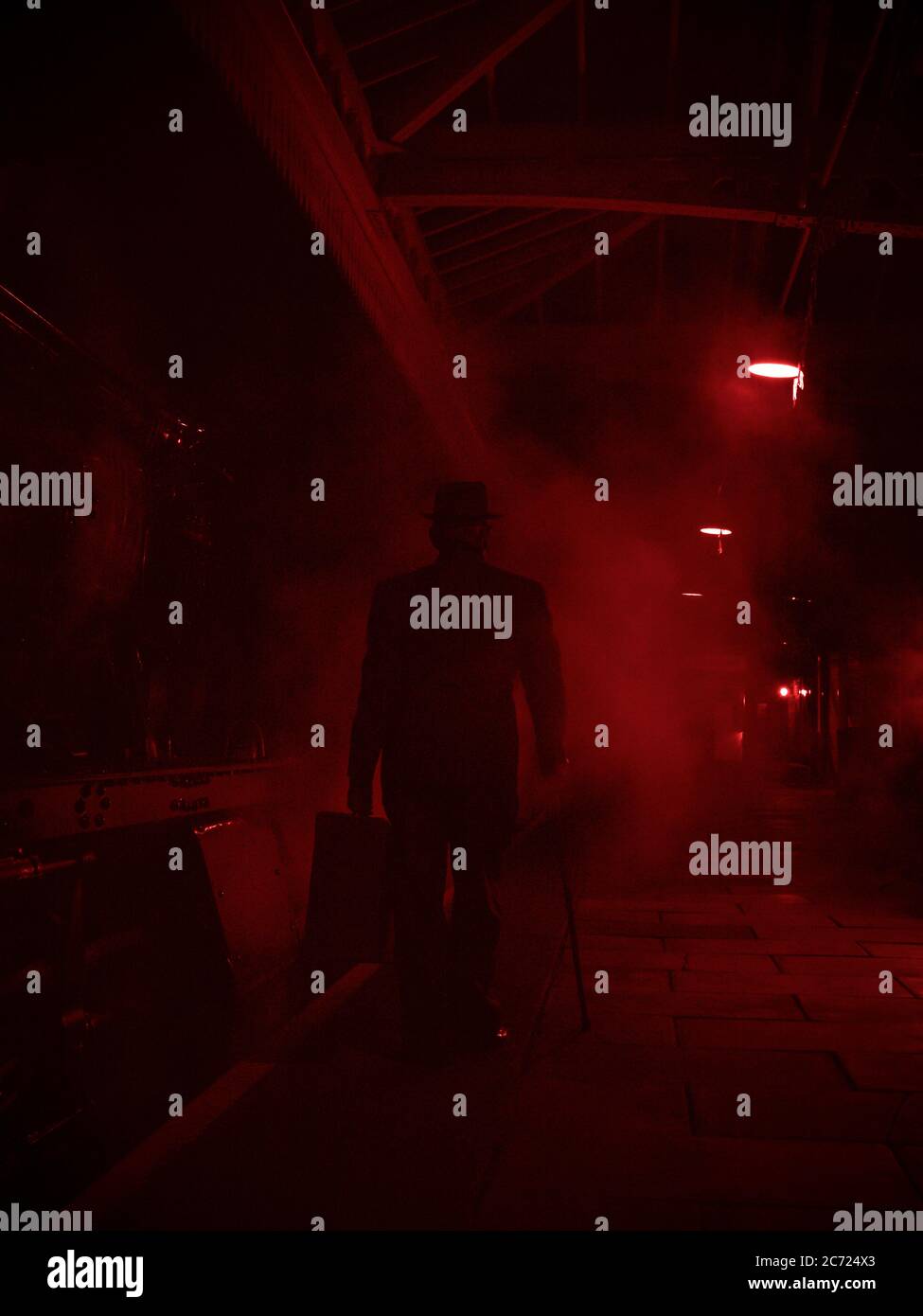 Rear view of man dressed in a suit and top hat walking along platform ...