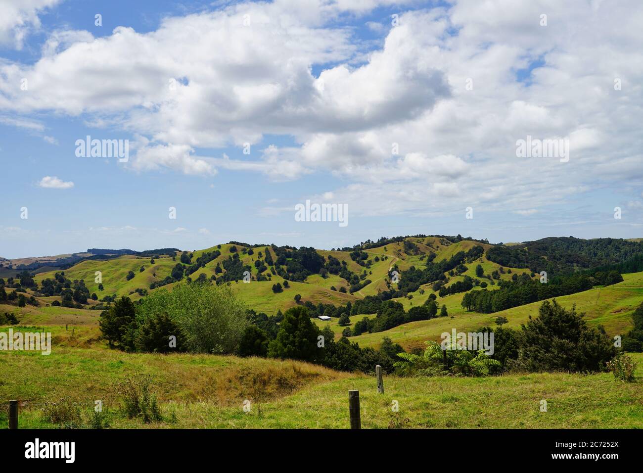 Typical New Zealand valley with green hills and a blue sky with clouds ...