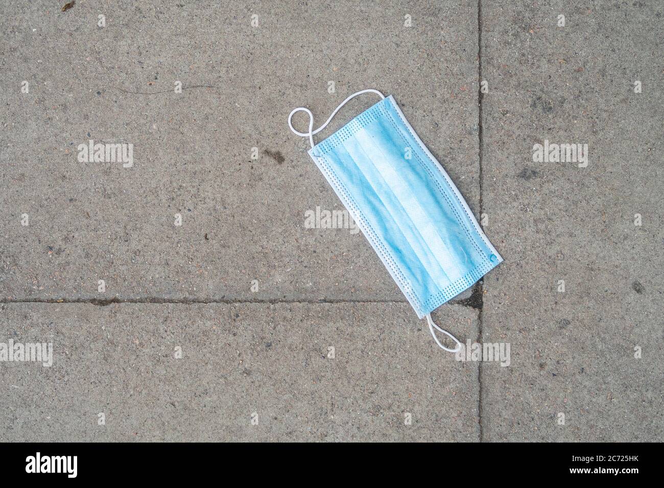 A used face mask on the ground on a street in London. A new common ...