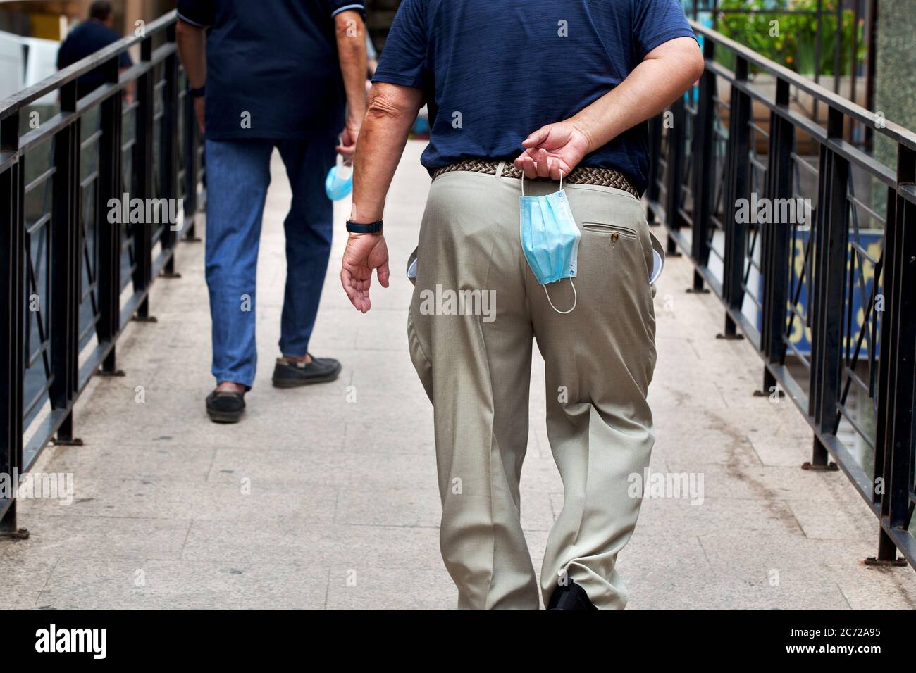 Man carrying face mask behind his back, Spain Stock Photo - Alamy