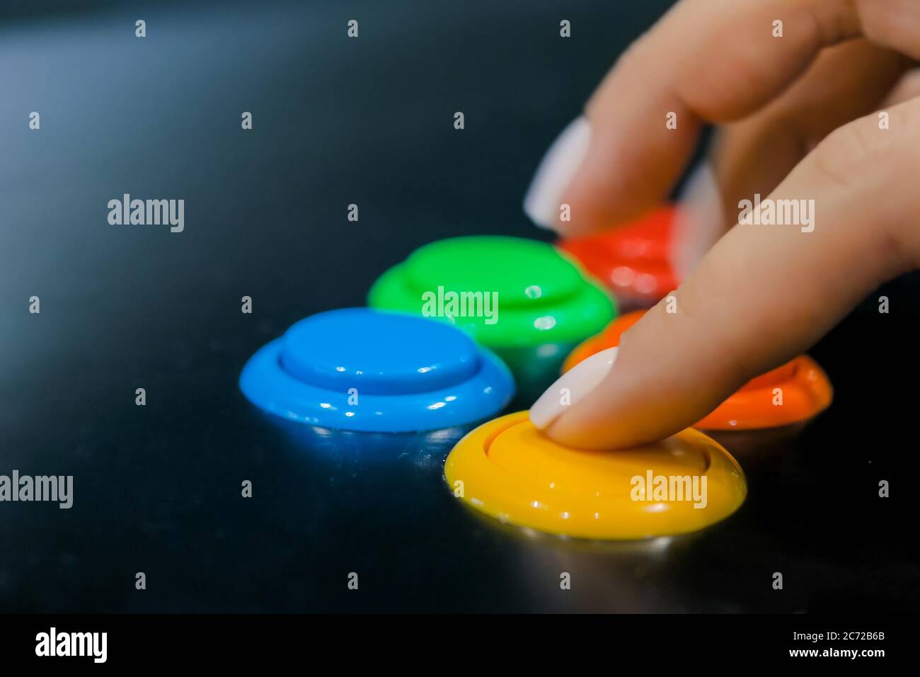 Woman hand using retro arcade machine and pushing bright colorful ...