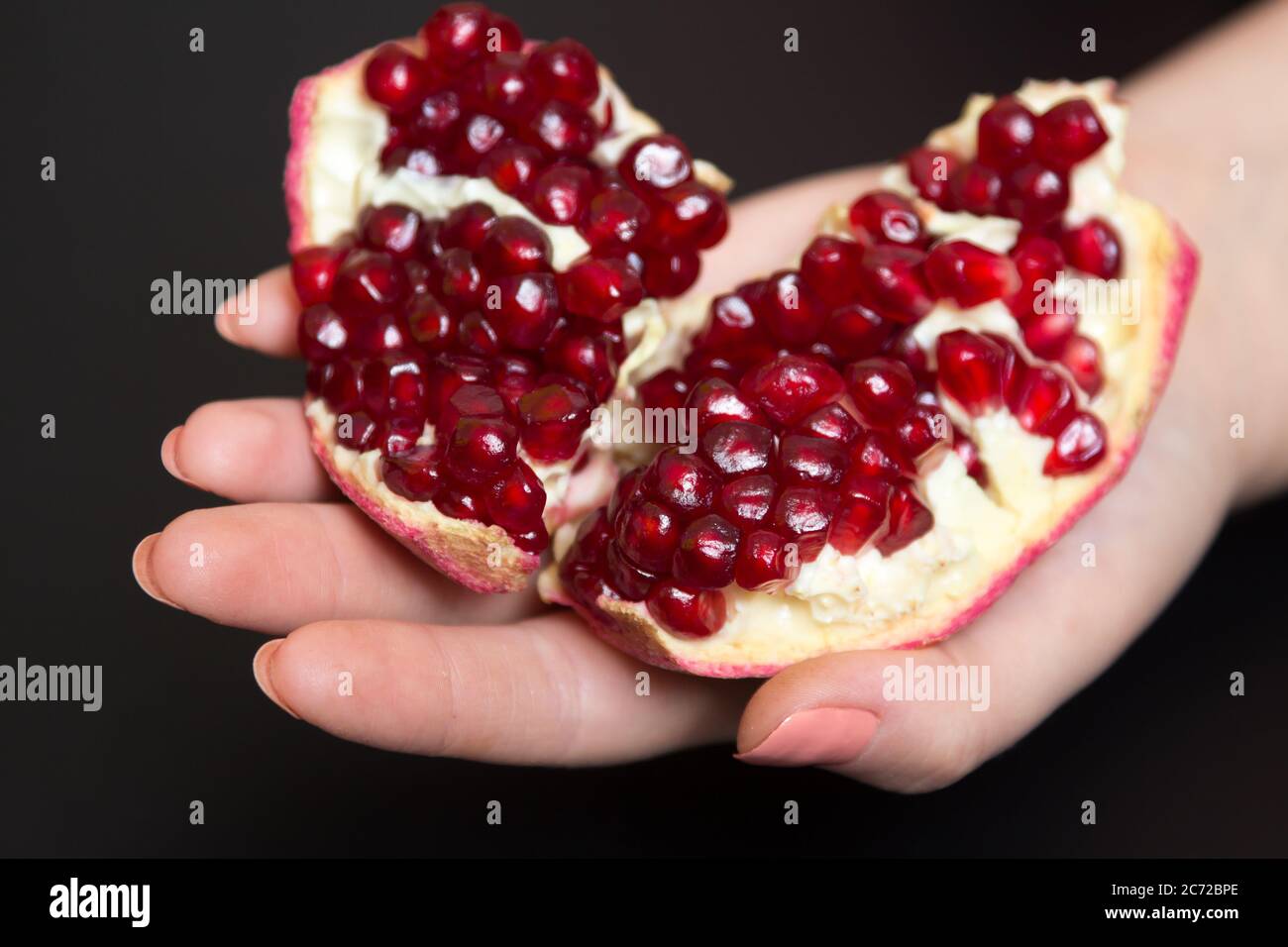 Purified pomegranate fruit in a female hand on a black background Stock ...
