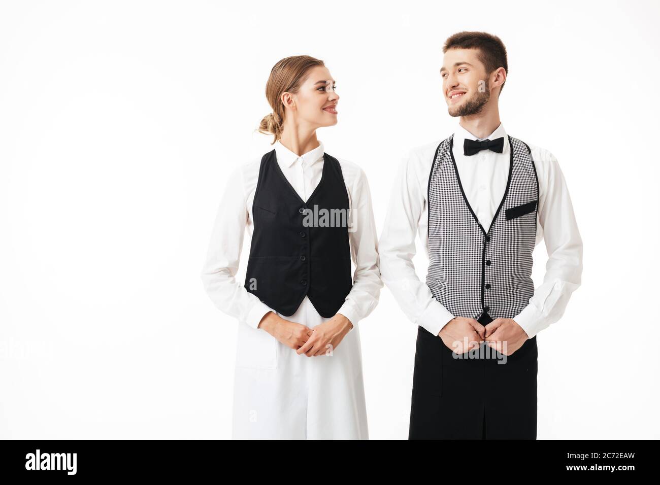 Young smiling waiter and pretty waitress in white shirts and vests ...