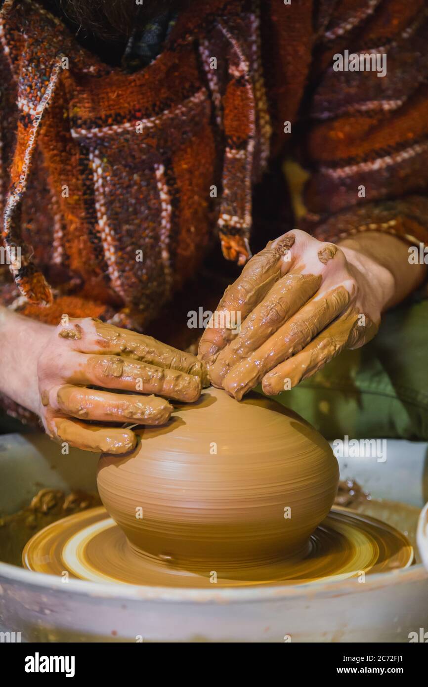Professional male potter making pot on pottery wheel at workshop ...