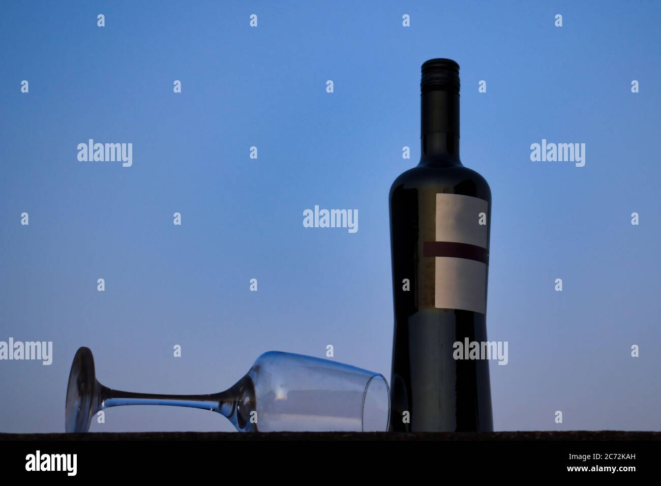 Bottle of red wine with a glass lying beside, under a blue sky Stock ...