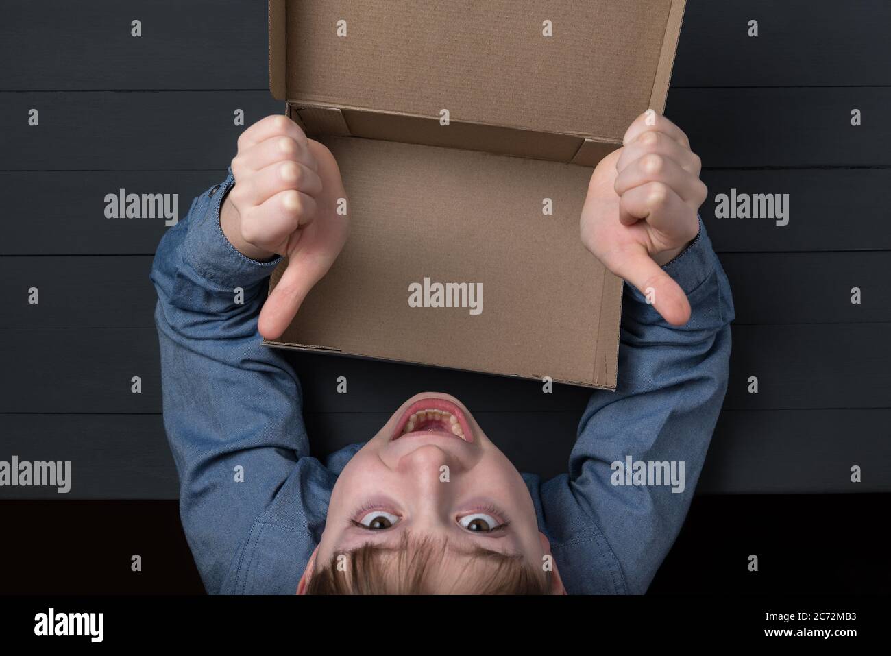 Funny boy with an open empty box shows thumbs up. Top view Stock Photo ...