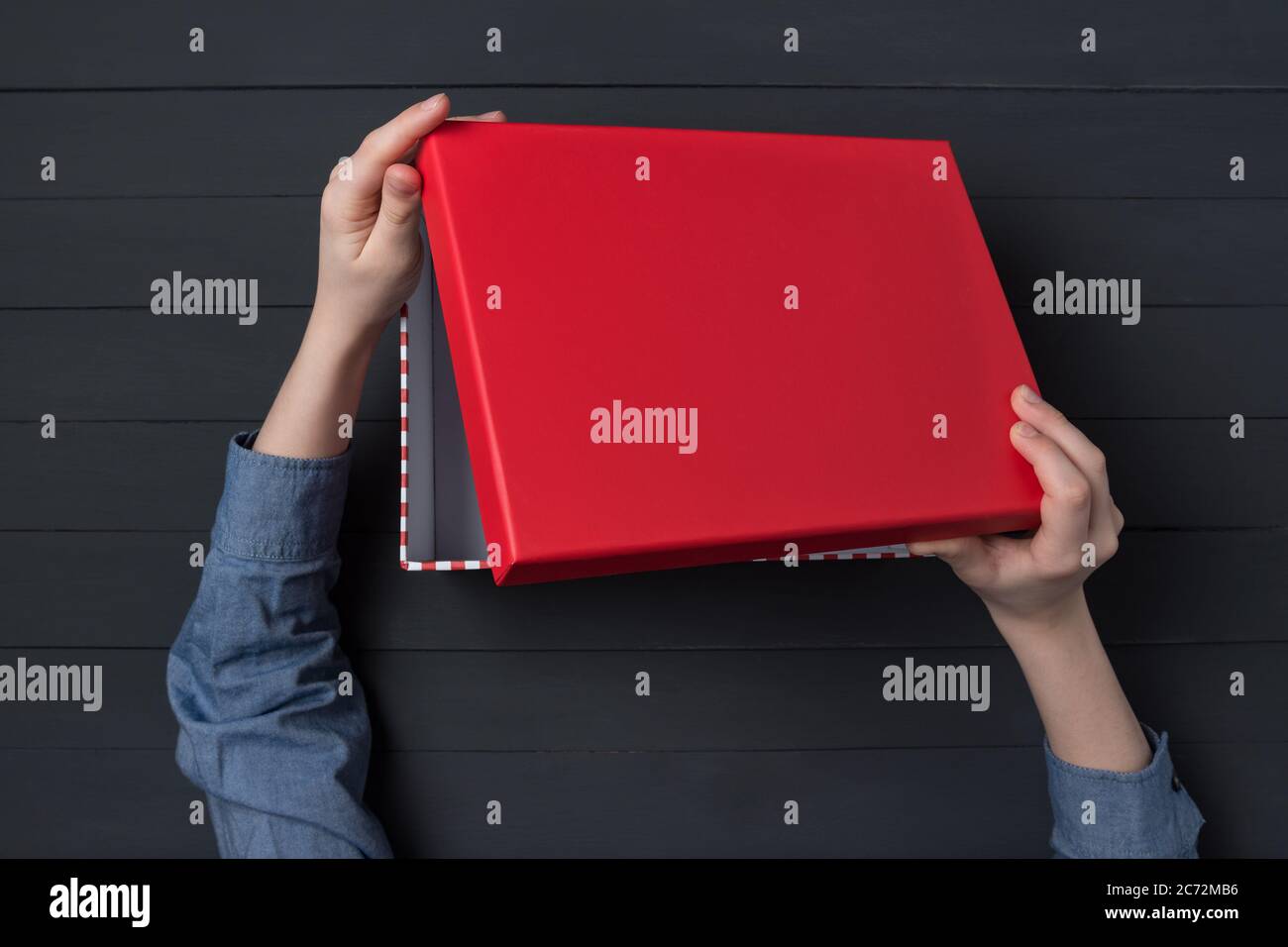 Children's hands open a gift box with a red lid. Top view Stock Photo ...