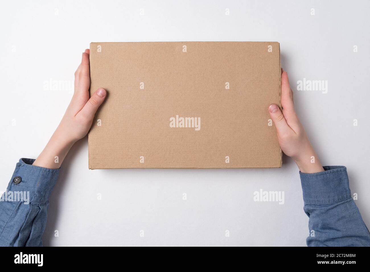 Craft paper box in children's hands on white background. Top view. Copy ...