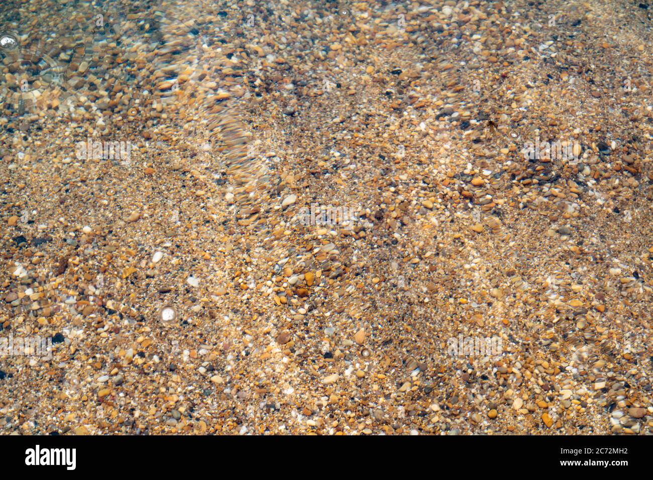 Sand and gravel under shallow crystal clear sea water with gentle ...