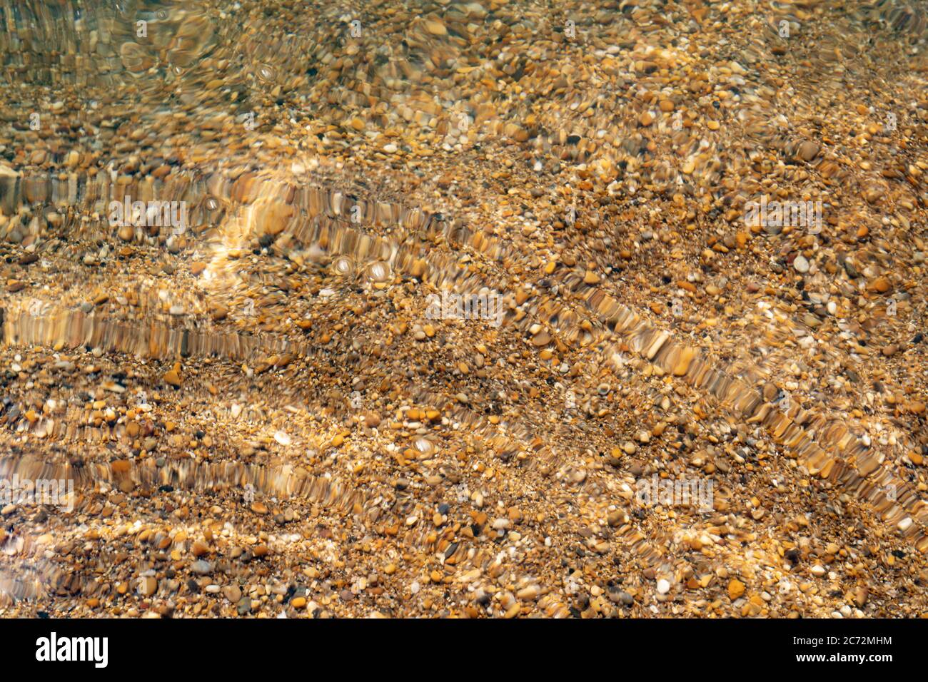 Sand and gravel under shallow crystal clear sea water with gentle ...