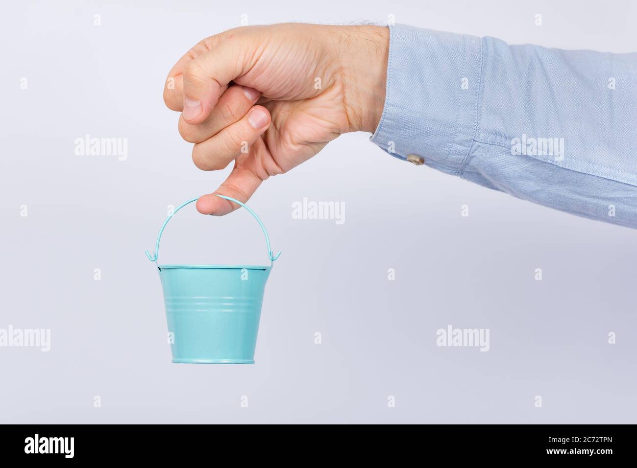 Man with little finger holding small toy bucket on white background ...