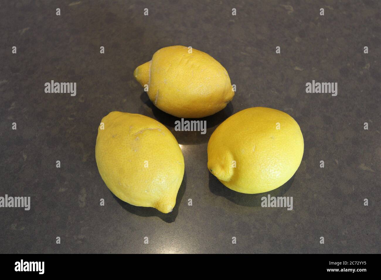 Three whole lemons on a gray surface Stock Photo - Alamy