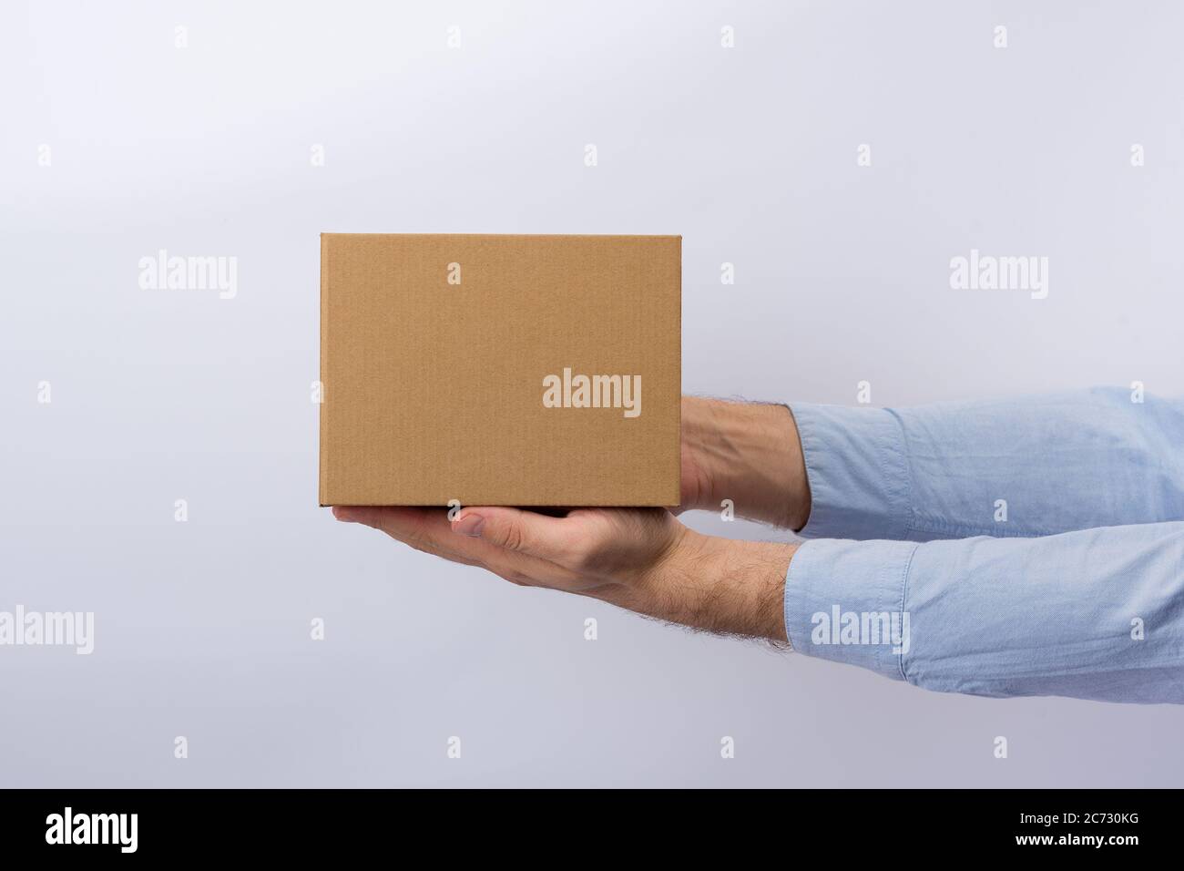 Man holding box at arm's length. White background. Square cardboard box ...