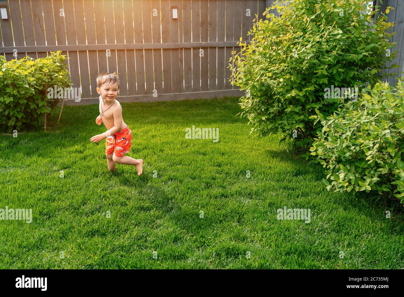 Child boy playing with water on backyard. The toddler boy having summer ...