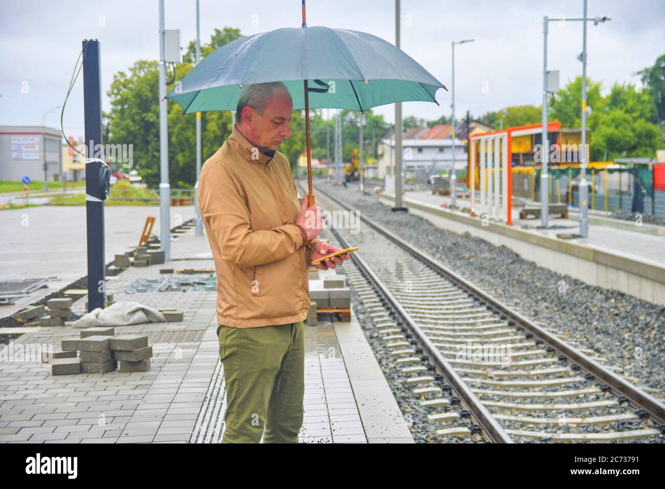 Portrait of a mature man with an umbrella standing on the platform of a ...