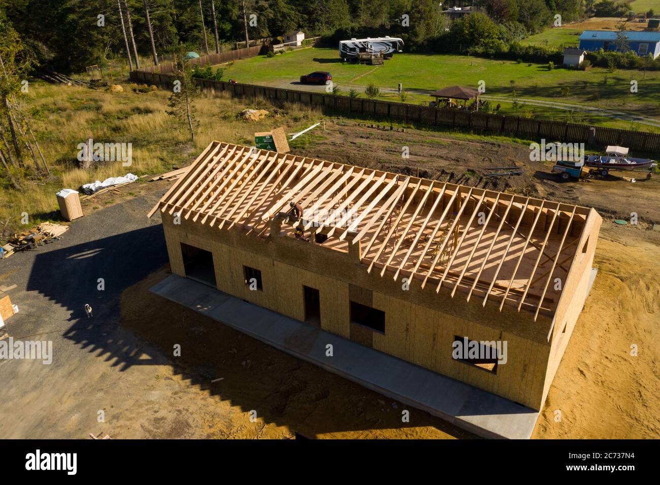 New home under construction in rural area with pine trees around it ...