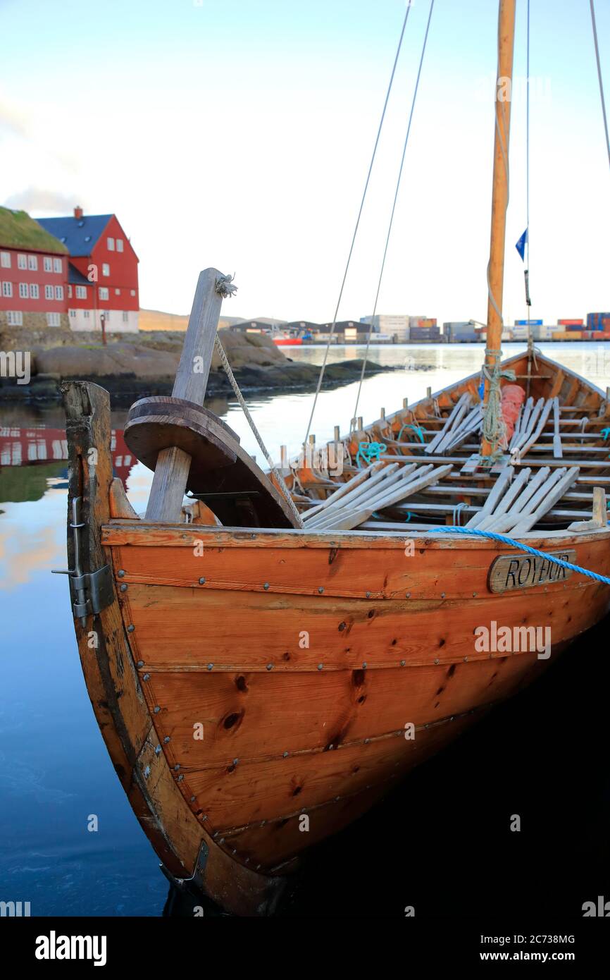 A traditional Faroese rowing boat docking in Torshavn harbor with turf ...
