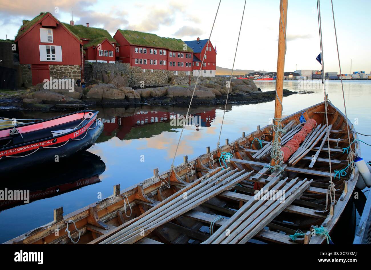 A traditional Faroese rowing boat docking in Torshavn harbor with turf ...
