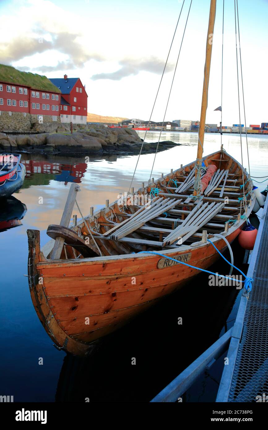 A traditional Faroese rowing boat docking in Torshavn harbor with turf ...