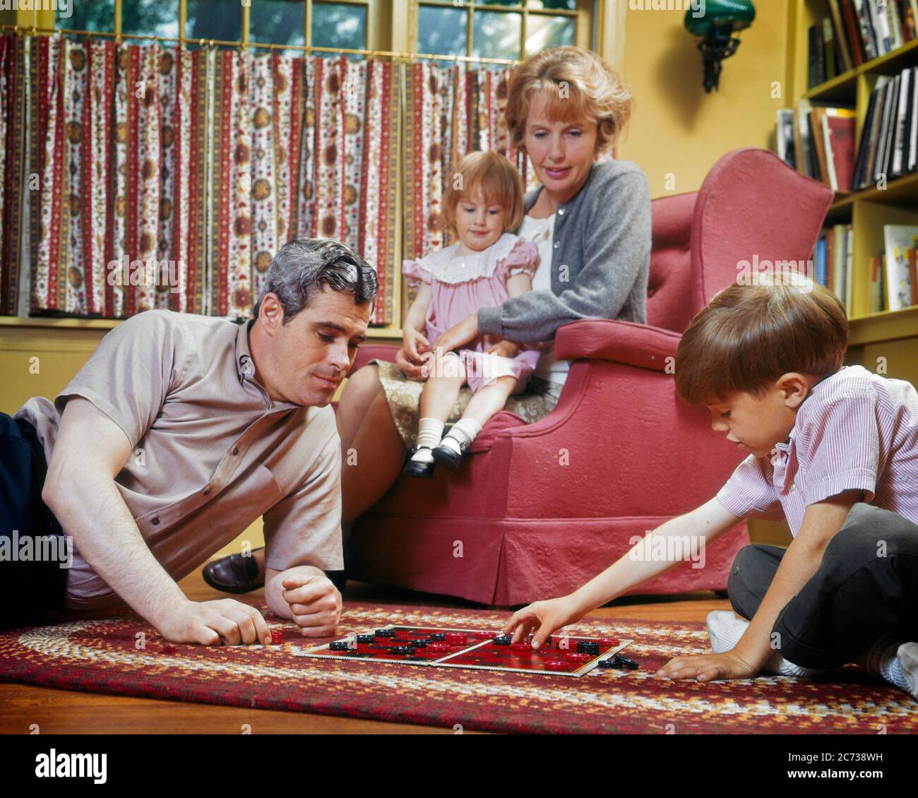 1970s FAMILY IN LIVING ROOM FATHER AND SON PLAYING CHECKERS GAME MOTHER ...