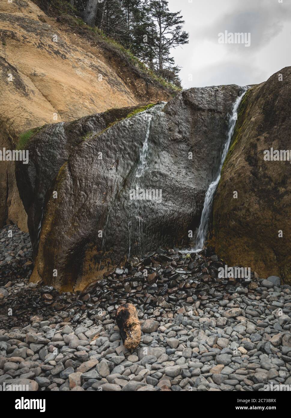 Beach waterfall at Hug Point State Park in Oregon. Vertical image Stock ...