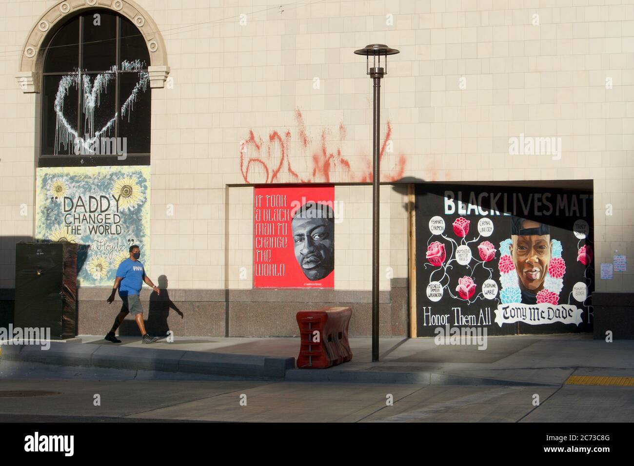 Masked pedestrian walking by Black Lives Matter protest street art on ...