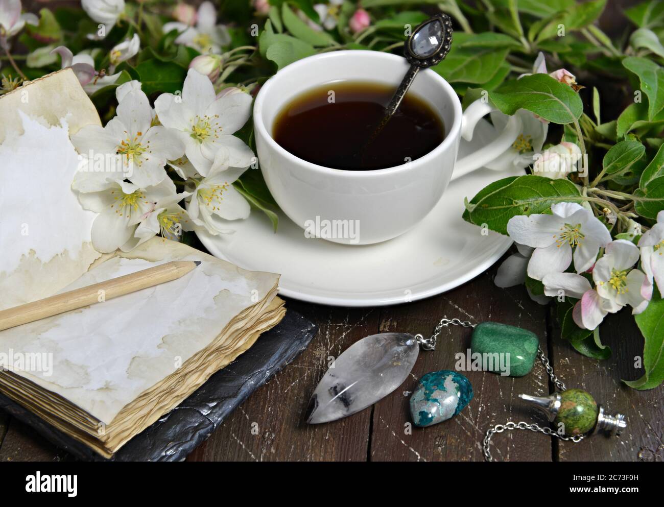 Cup of tea with open diary and apple tree flowers on planks. Esoteric ...