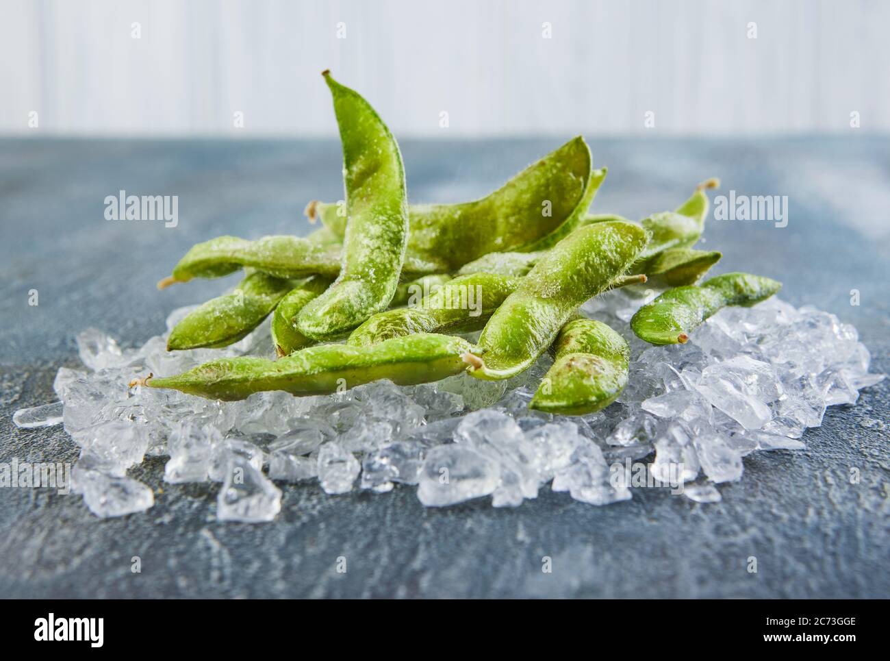 Frozen Edamame or soybeans in the mix with crushed ice on a blue ...