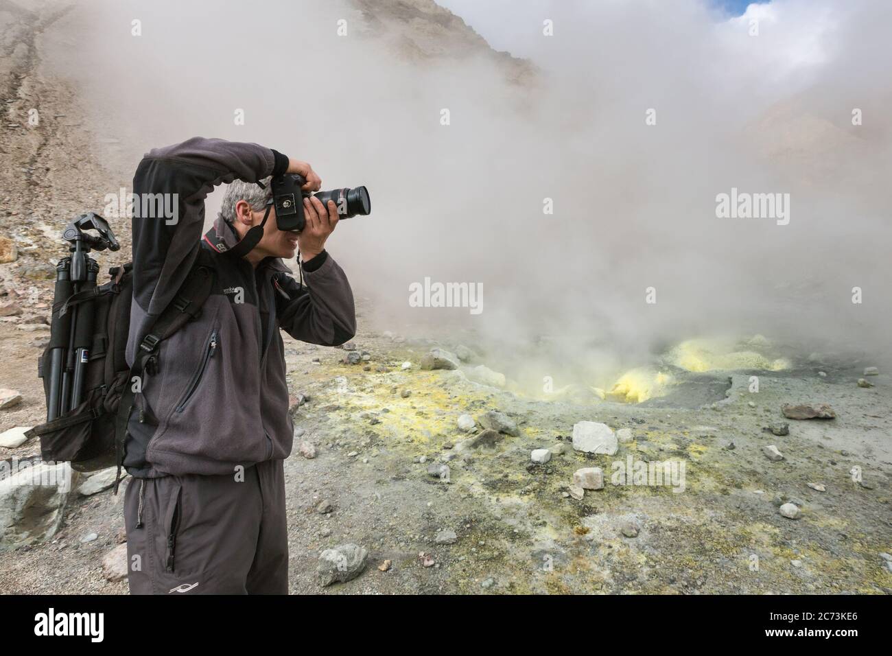 Male photographer takes pictures volcanic landscape, fumes aggressive ...