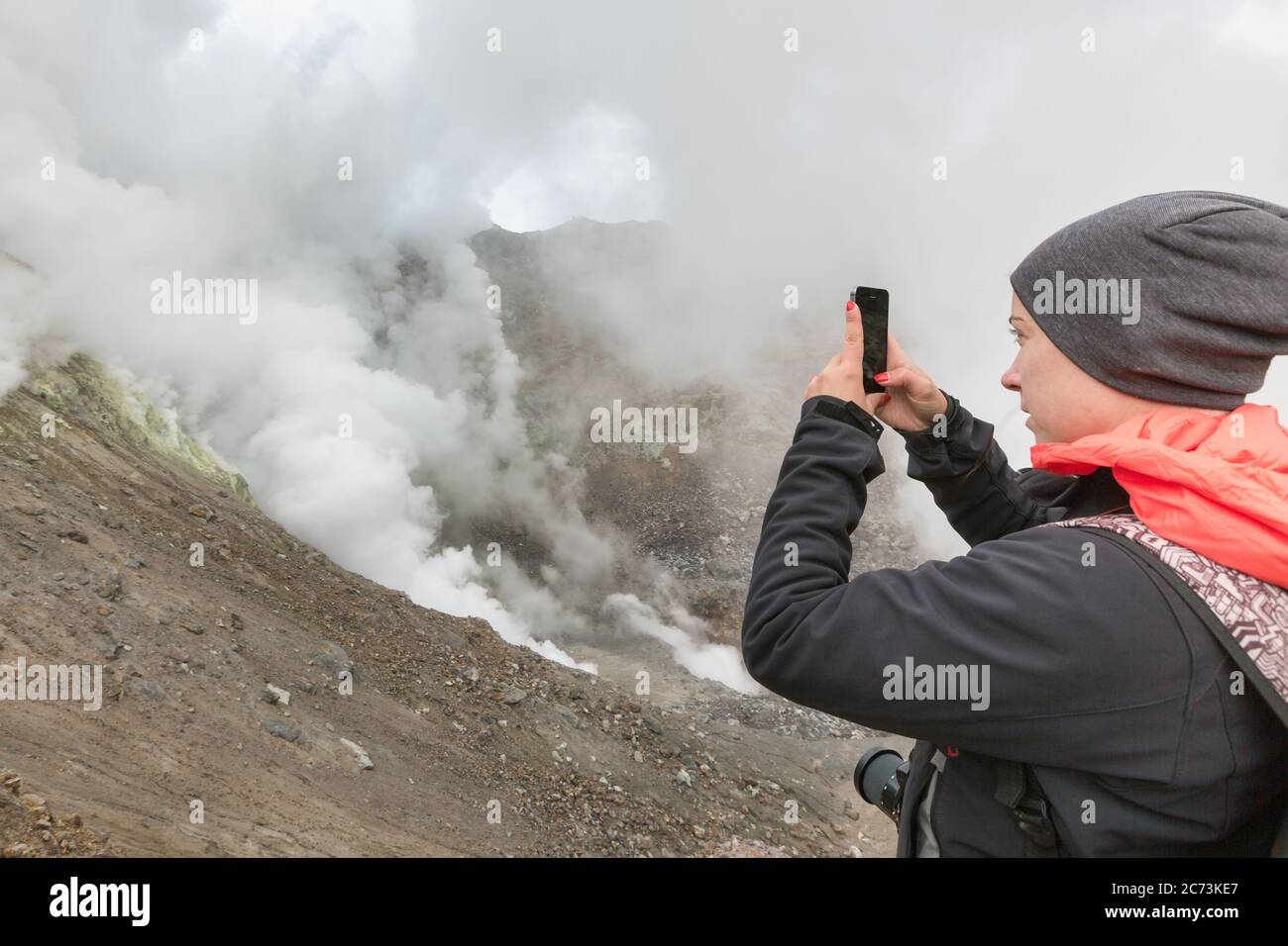 Girl tourist takes pictures of stunning volcanic landscape, aggressive ...