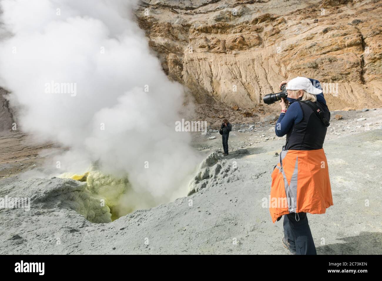 Woman photographer tourist takes pictures of volcanic landscape, hot ...
