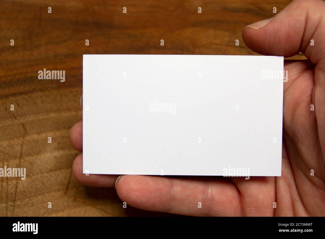 white empty card in male caucasian hand on a wooden background. concept ...