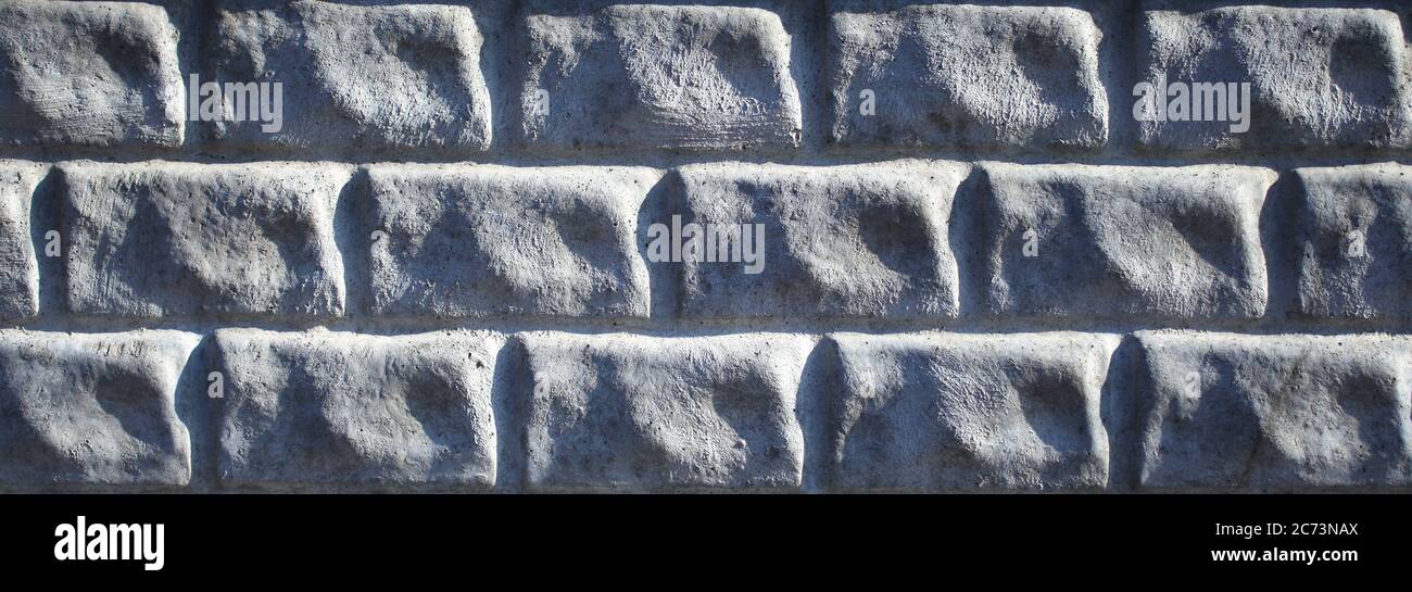 Light-grey decorative stone wall, made of regular shape bricks ...