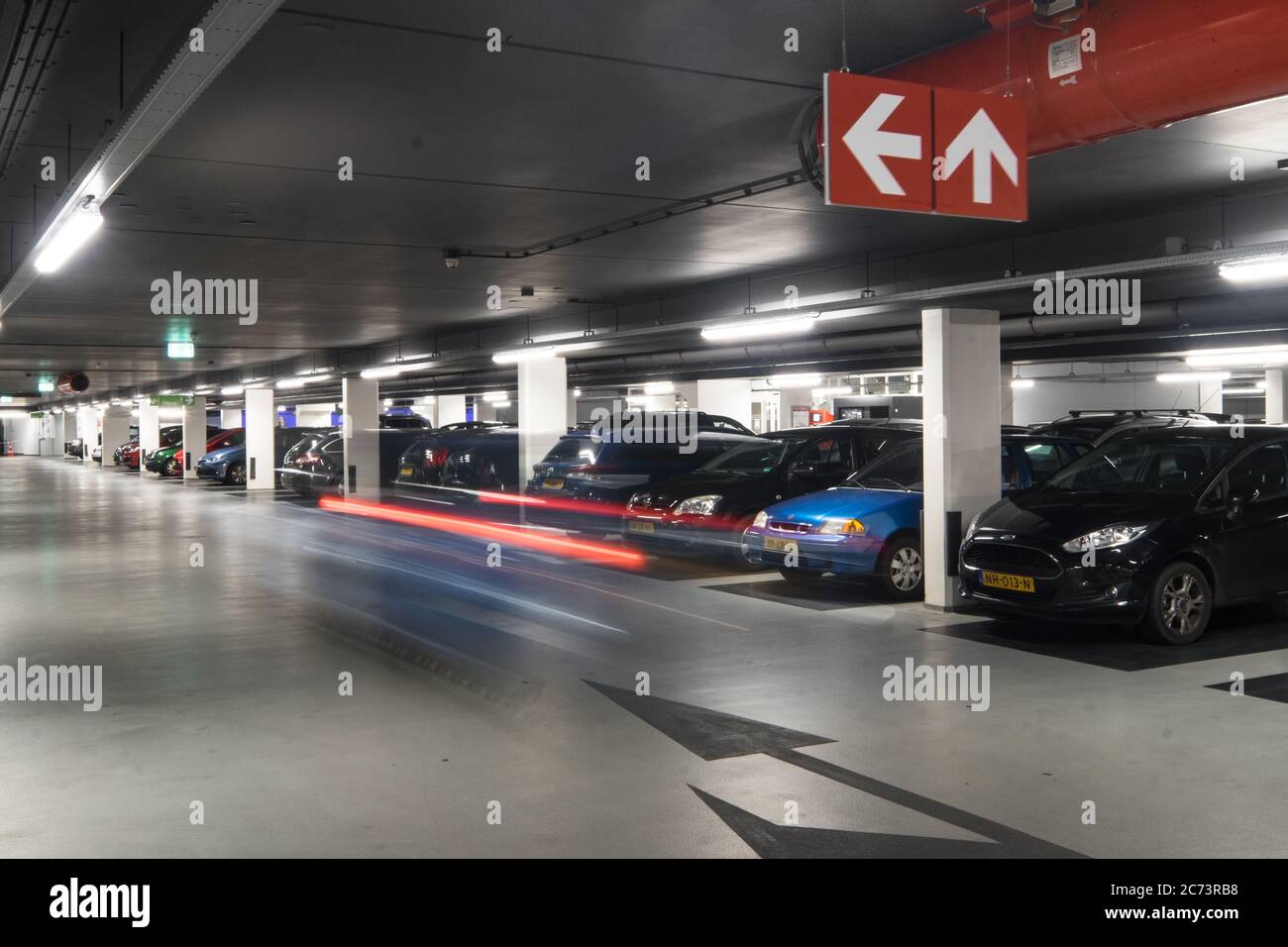 Underground parking garage with parked cars and stripes of light from a ...