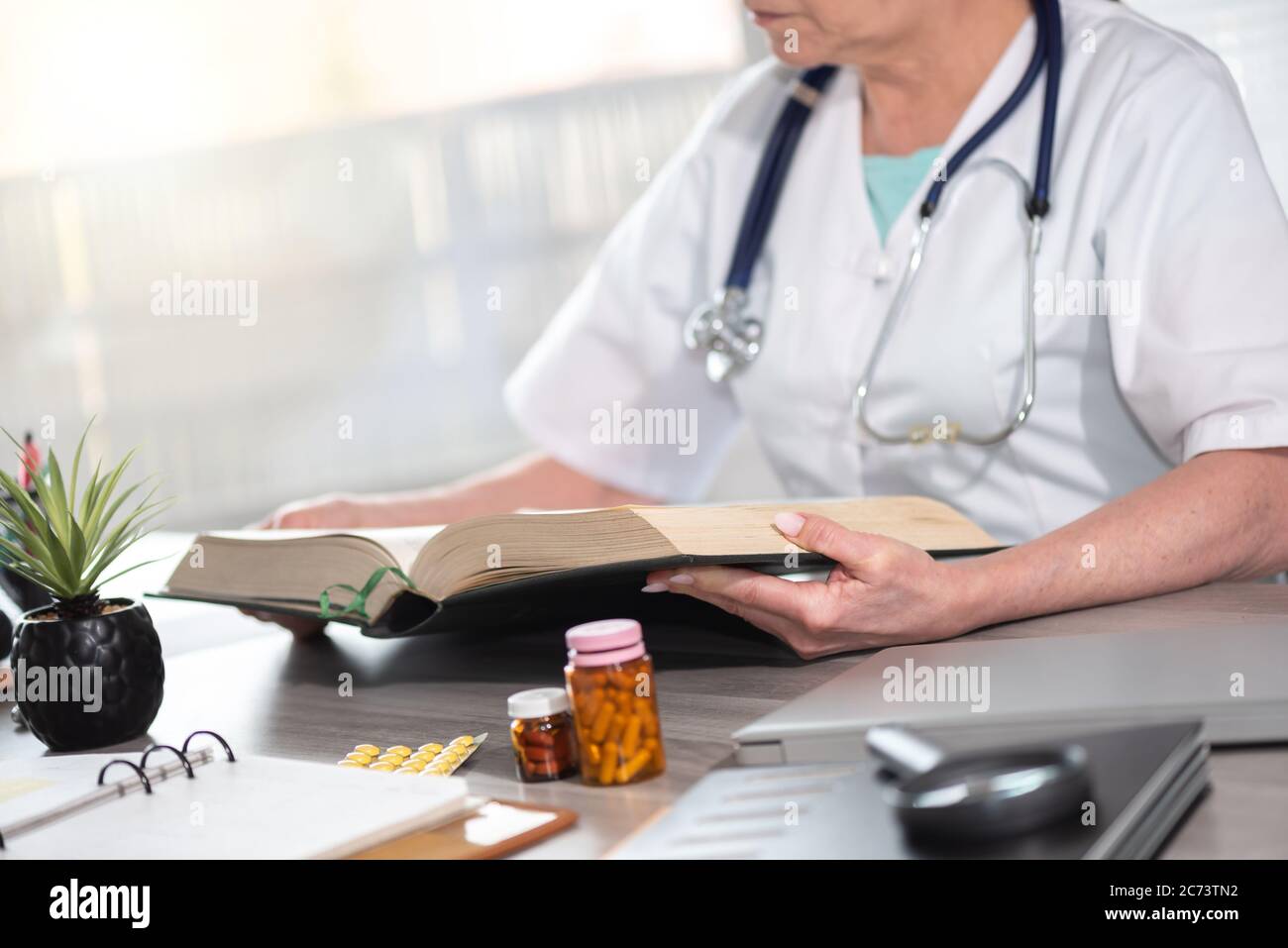 Female doctor reading a textbook in medical office Stock Photo - Alamy