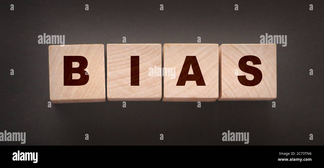 The word BIAS, spelt with wooden letter tiles over a black background ...