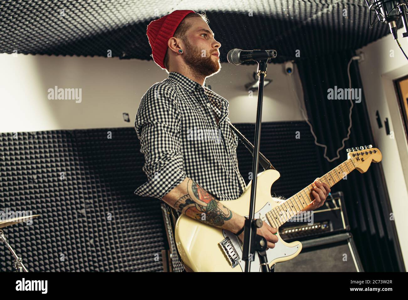 professional caucasian singer play electric guitar in recording studio ...
