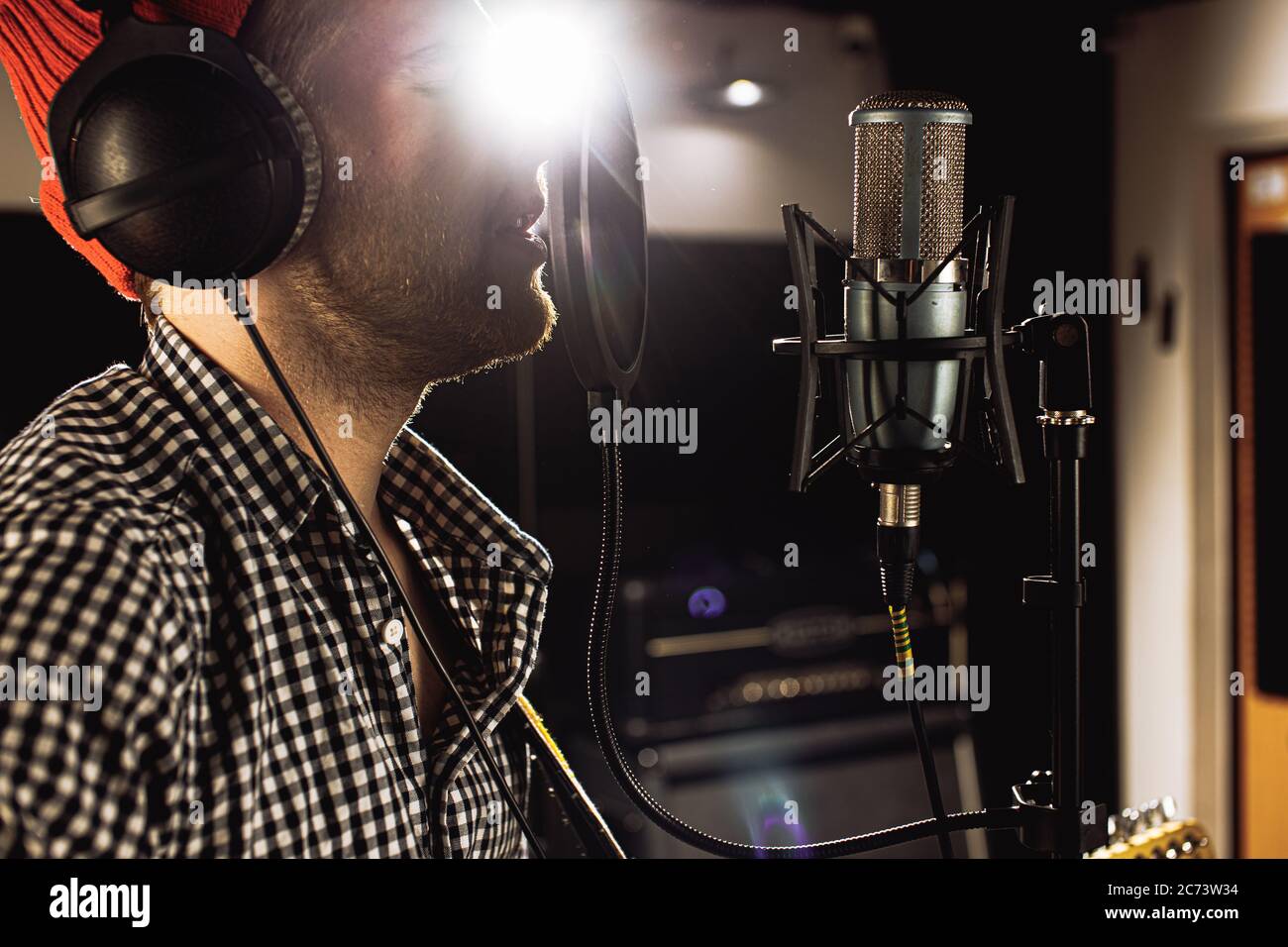 side view on caucasian young man singing on microphone in recording ...