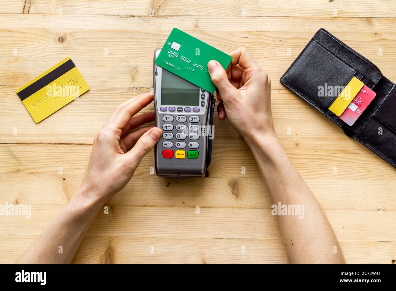 Payment by credit card. Hand hold card near terminal on wooden desk top ...