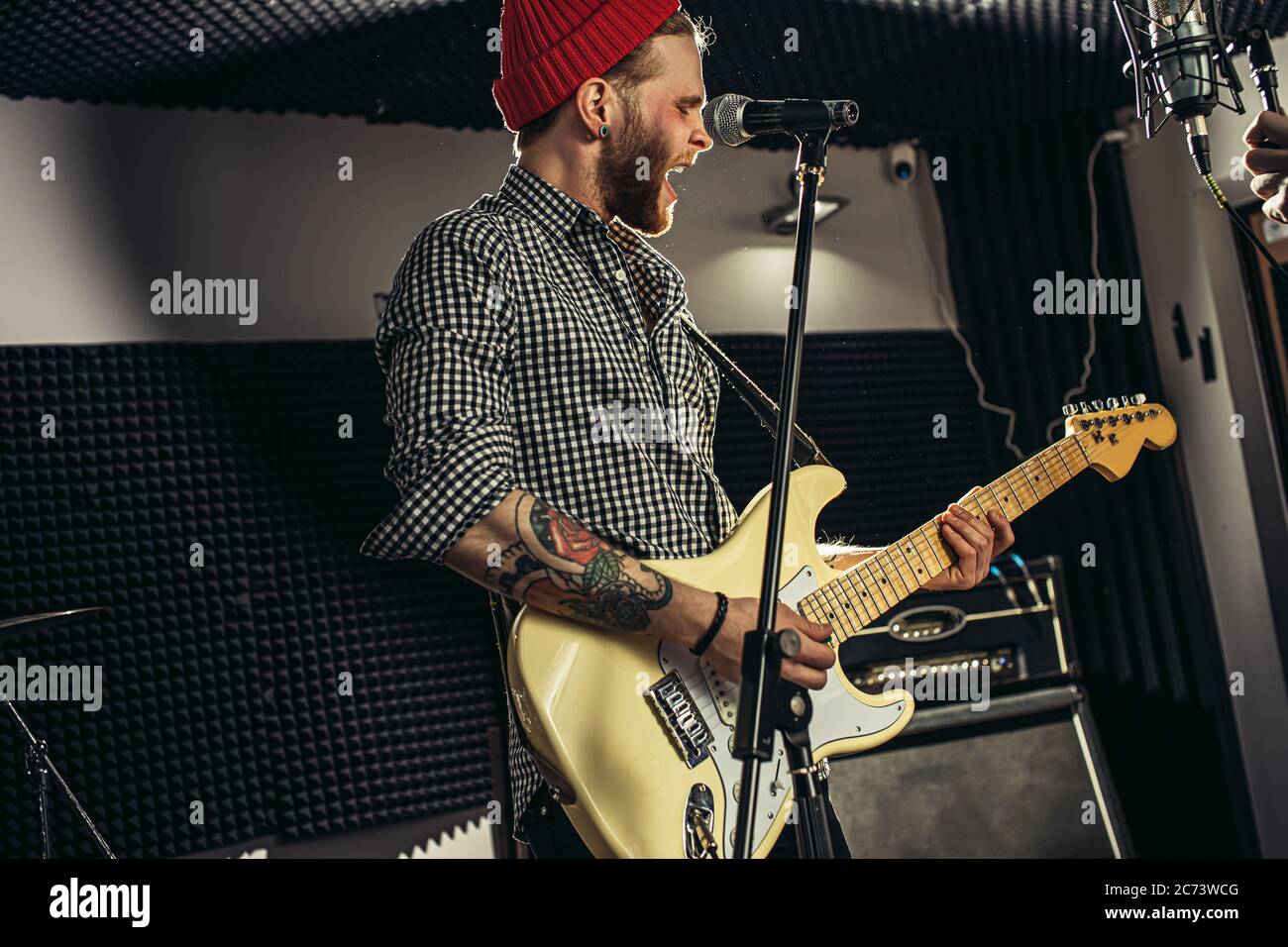 emotional caucasian singer play electric guitar and sing on microphone ...