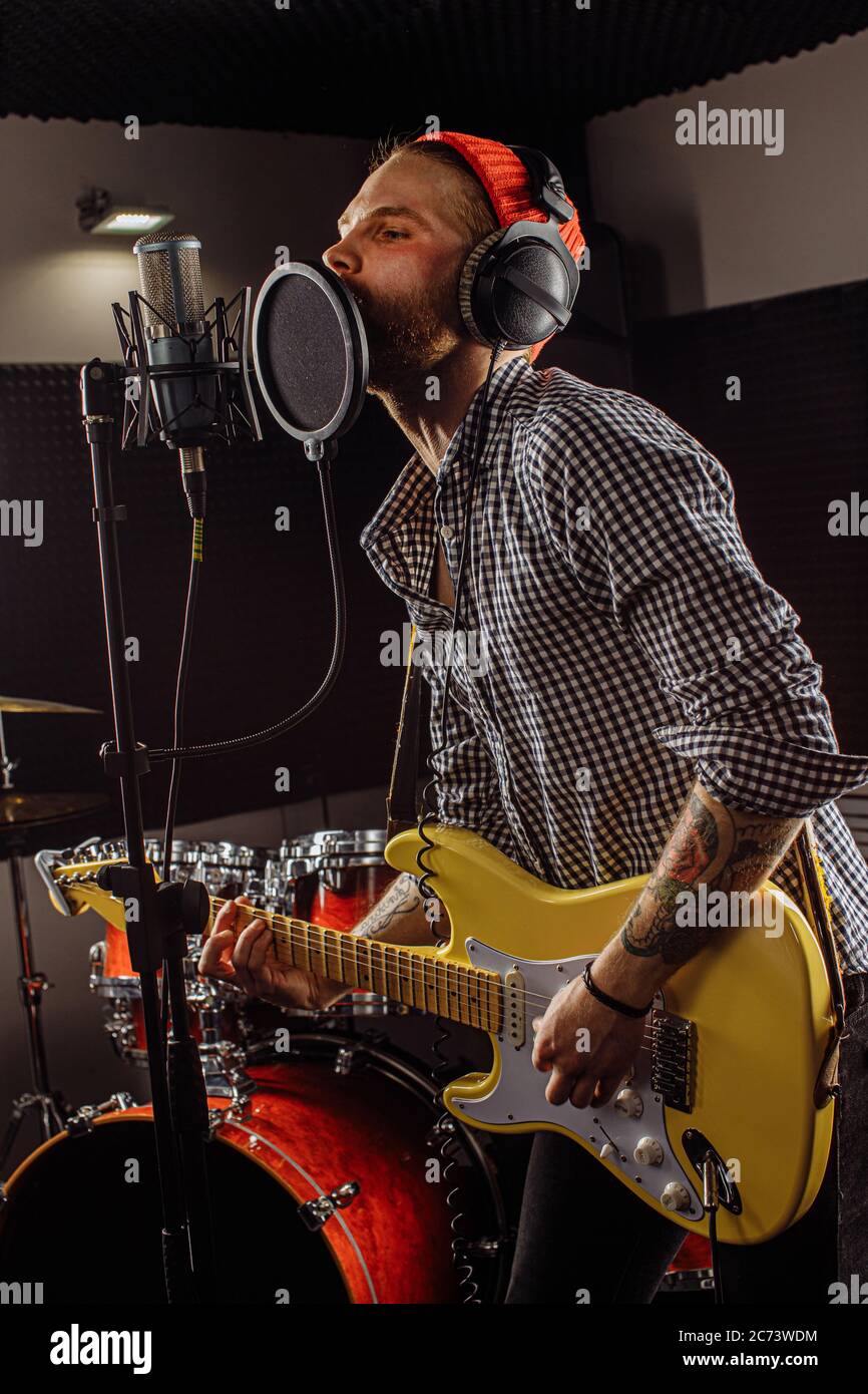 young talented caucasian musician play guitar and sing on microphone ...