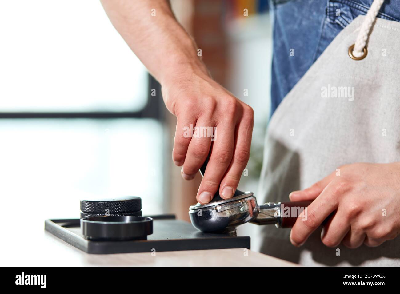 Close up of hands pressing coffee in tamper, push with effort, making ...