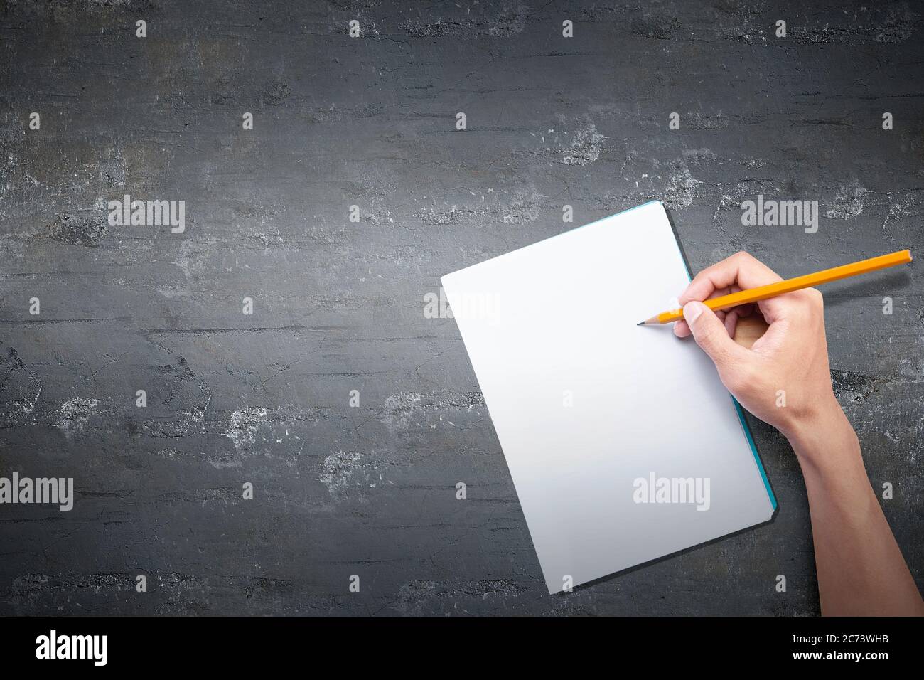 Hand with pencil writing in the book with a black background. Back to ...