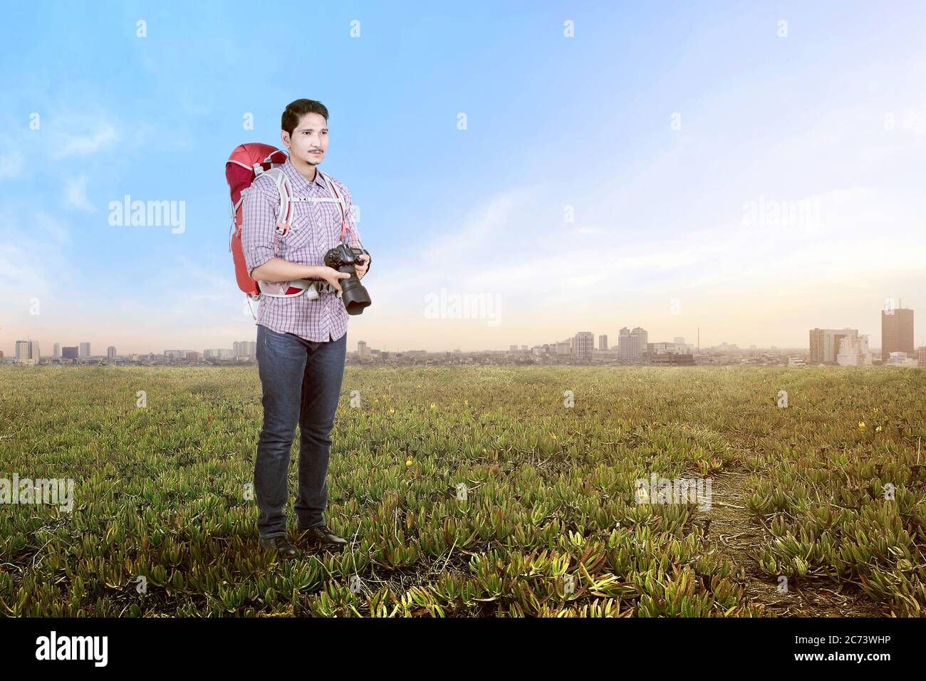Asian man with a backpack holding the camera on the meadow field. World ...