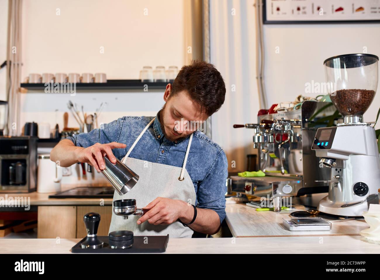 Mindful calm barista with thick beard, wears apron, bows head, looks ...
