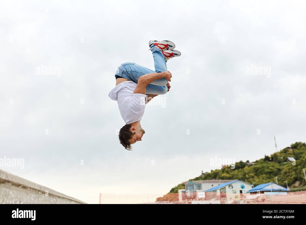young man throwing a somersault outdoors, full length side view photo ...