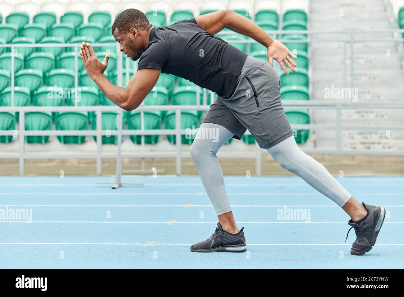 strong motivated active sportsman starting his sprint on running track ...
