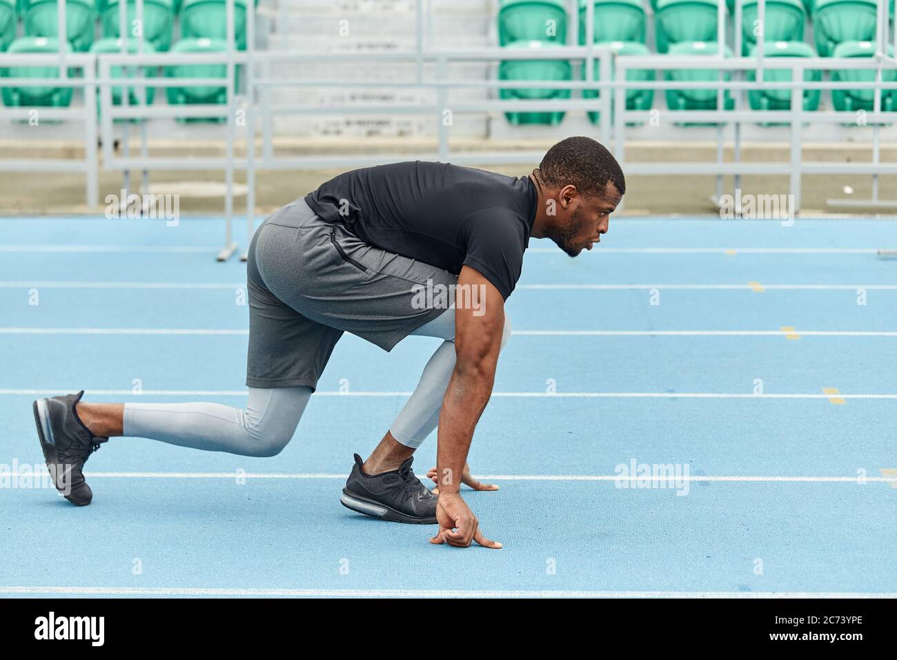 muscular runner standing in the croach, low start at the stadium. full ...